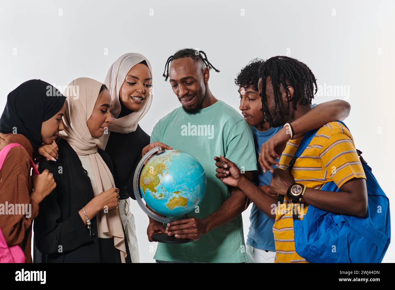 A diverse group of students is gathered around a globe, engrossed in ...