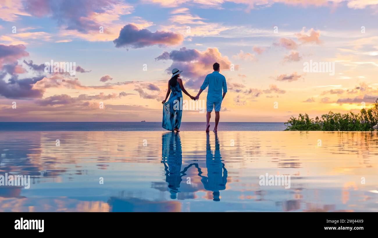 Young men and women watching sunset with reflection in the infinity ...