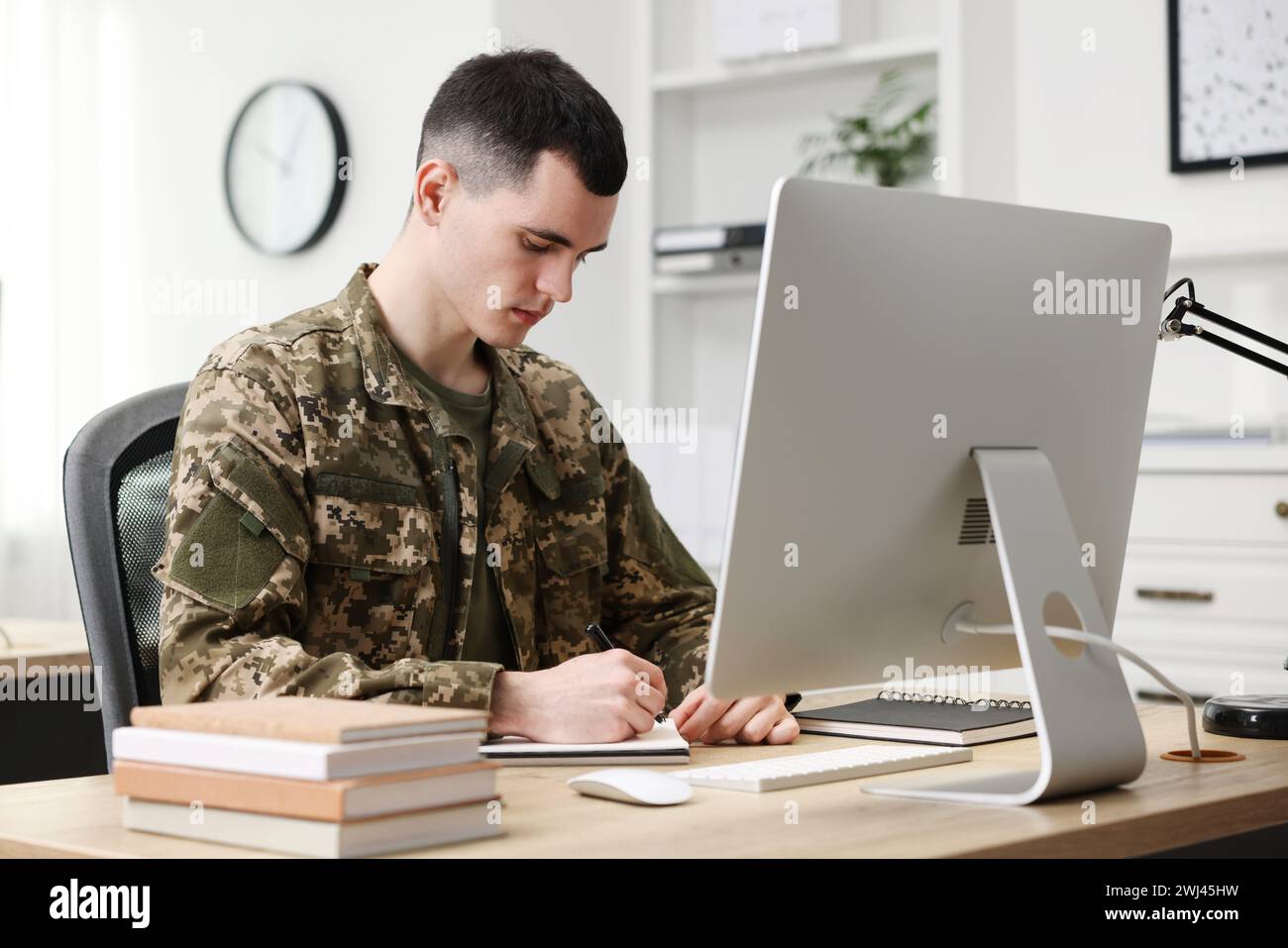Military education. Young student in soldier uniform learning at wooden ...