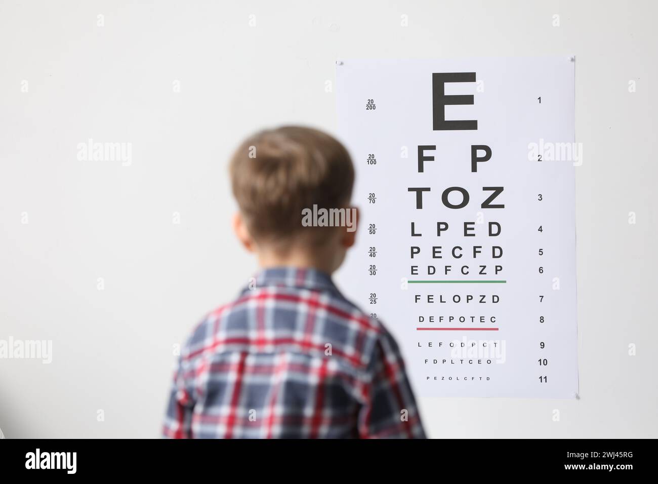 Eyesight examination. Little boy looking at vision test chart indoors ...