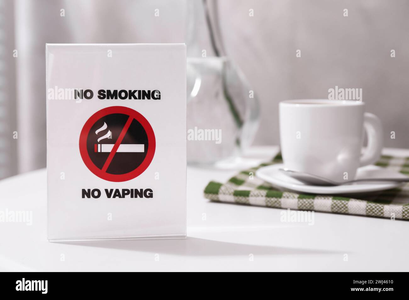 No Smoking No Vaping sign and cup of coffee on white table indoors ...