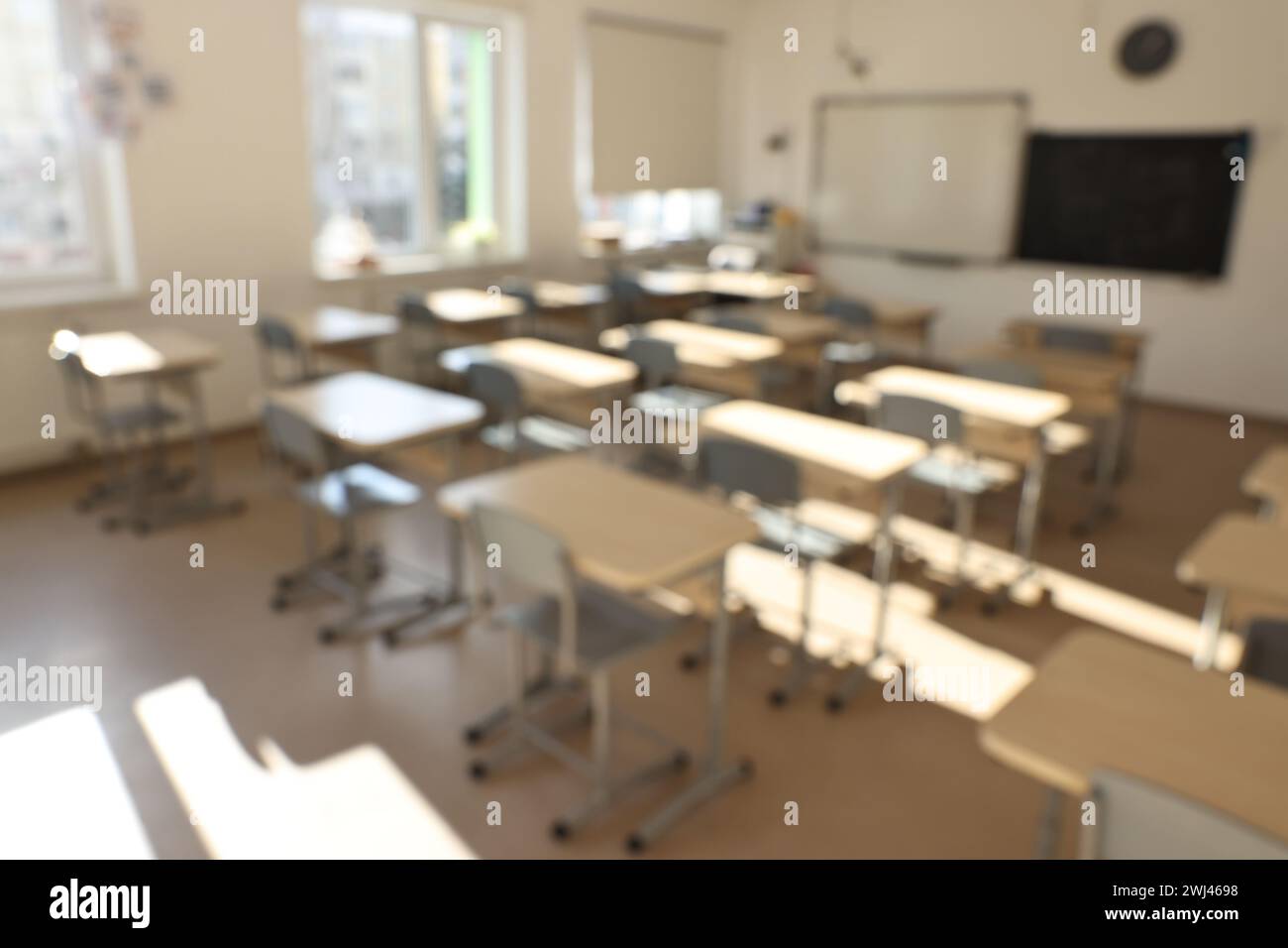 Blurred view of empty school classroom with desks, windows and chairs ...