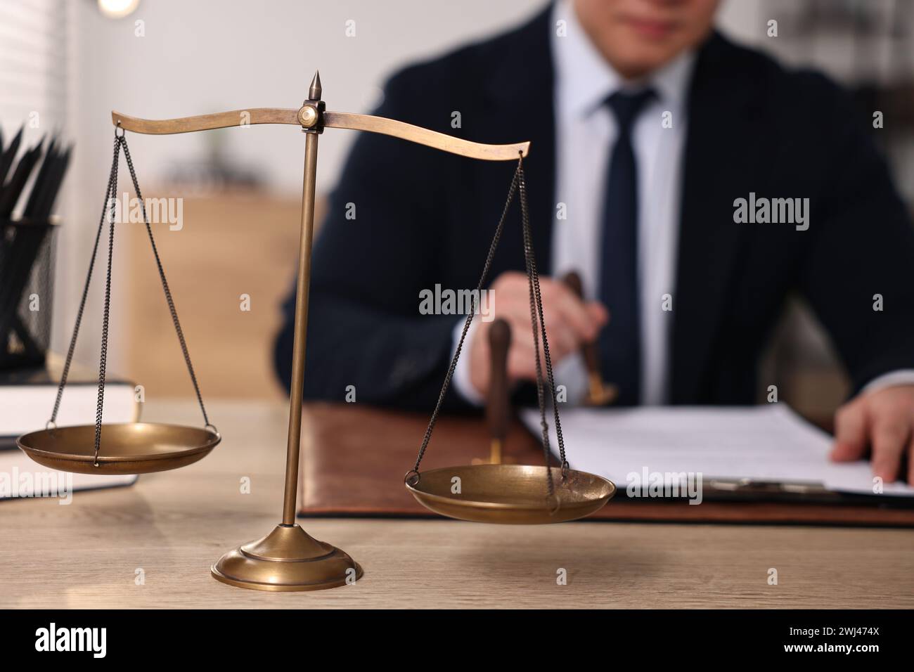 Notary stamping document at wooden table in office, focus on scales of ...