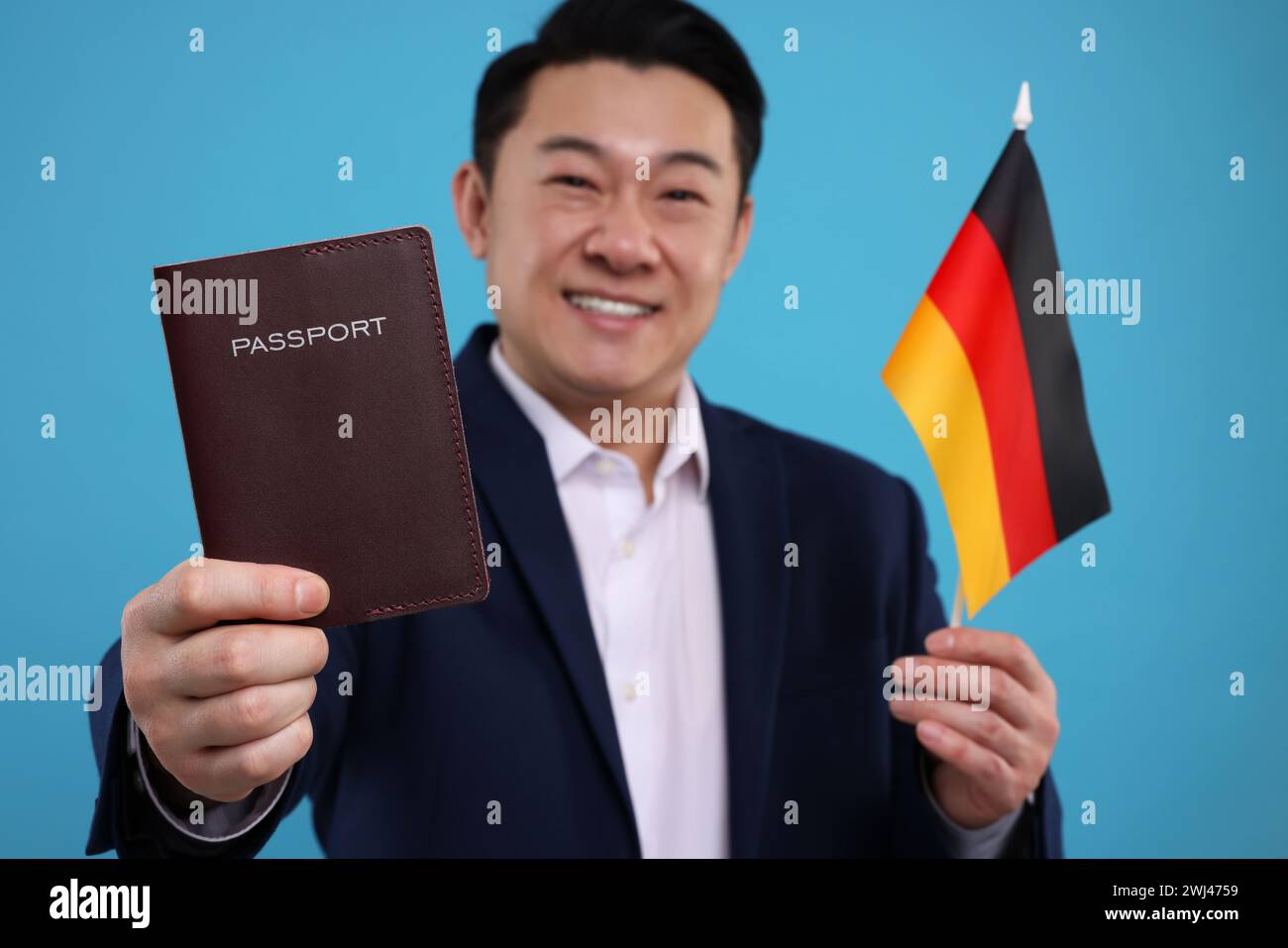 Immigration. Happy man with passport and flag of Germany on light blue ...