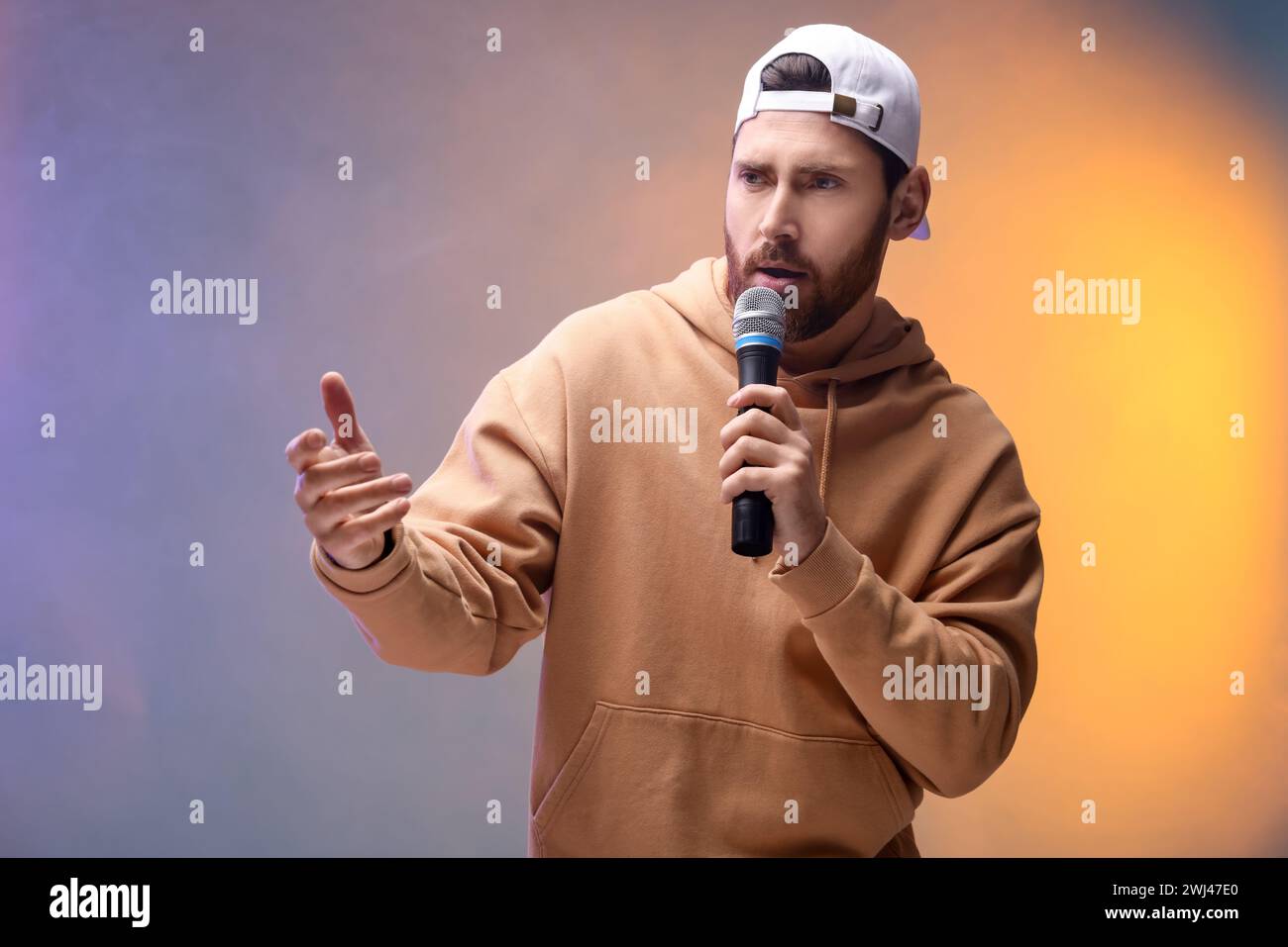 Singer with microphone rapping in color lights Stock Photo - Alamy