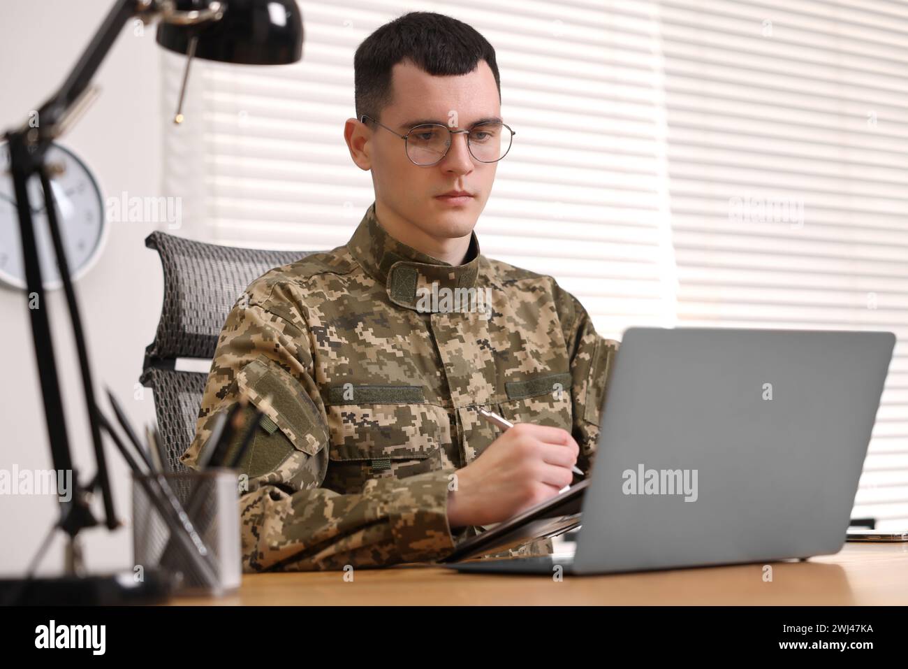 Military service. Young soldier working at table in office Stock Photo ...
