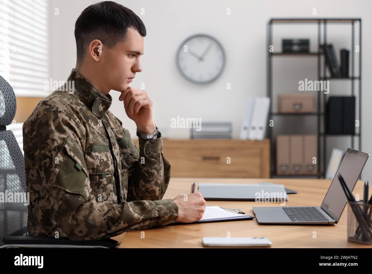 Military service. Young soldier working at wooden table in office Stock ...