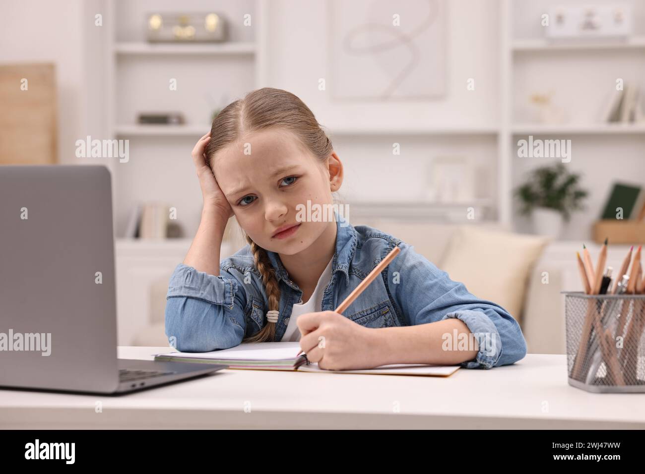 Little girl suffering from headache while doing homework at home Stock ...