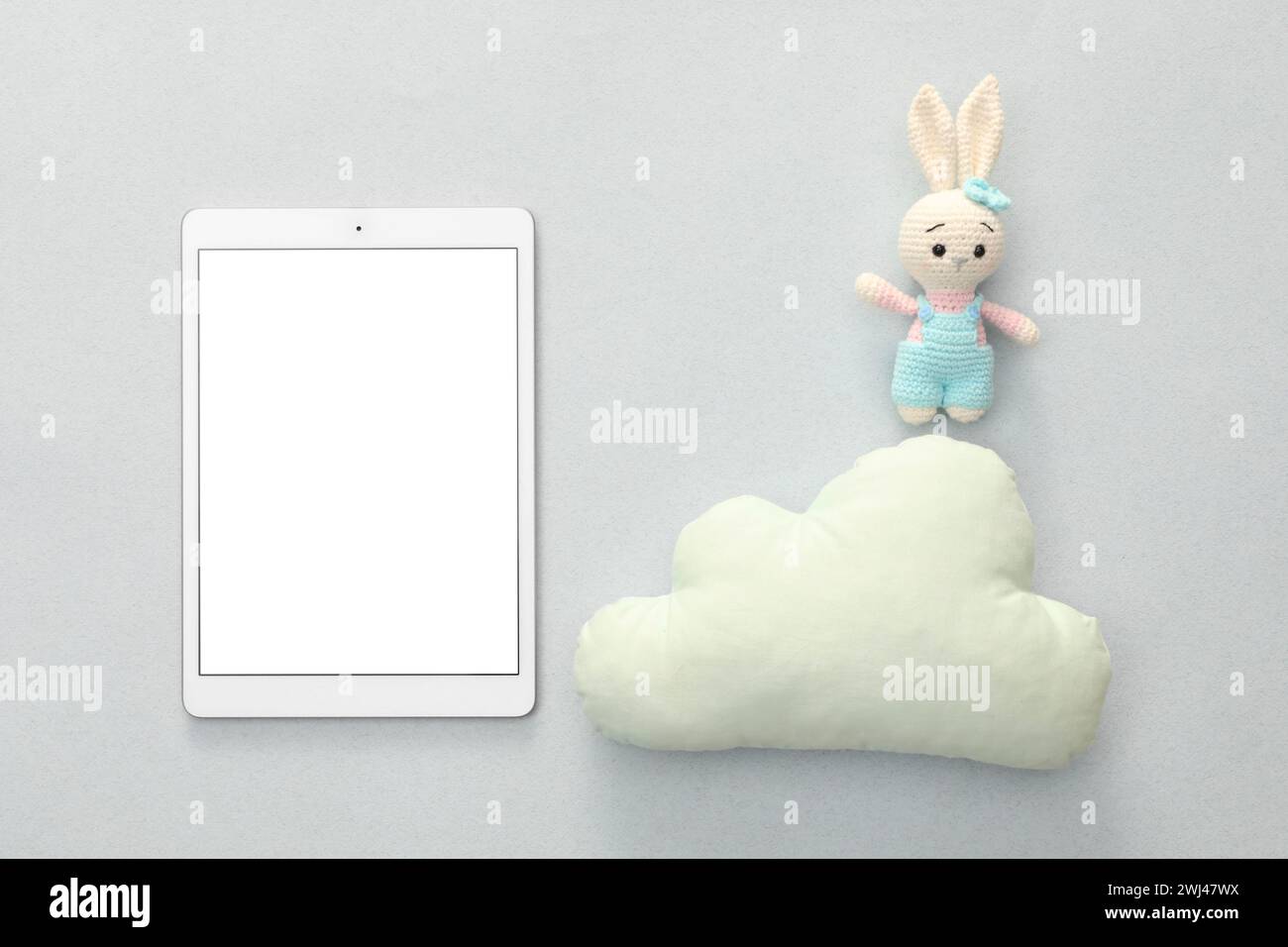 Modern tablet, toy cloud and bunny on light background, flat lay. Space ...