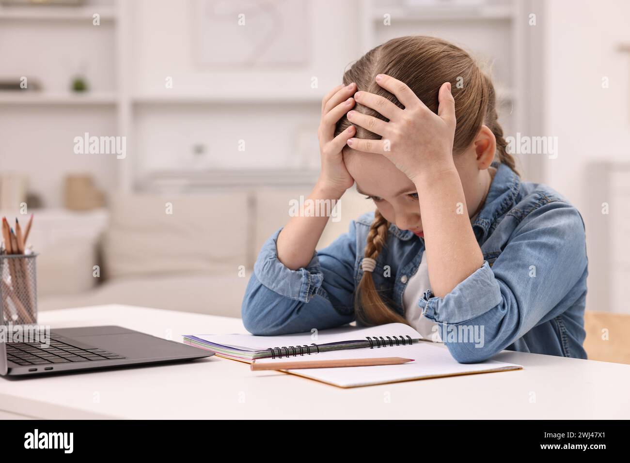Little girl suffering from headache while doing homework at home Stock ...