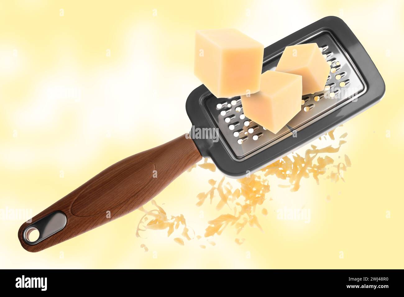 Grating cheese with hand grater on yellow background Stock Photo - Alamy