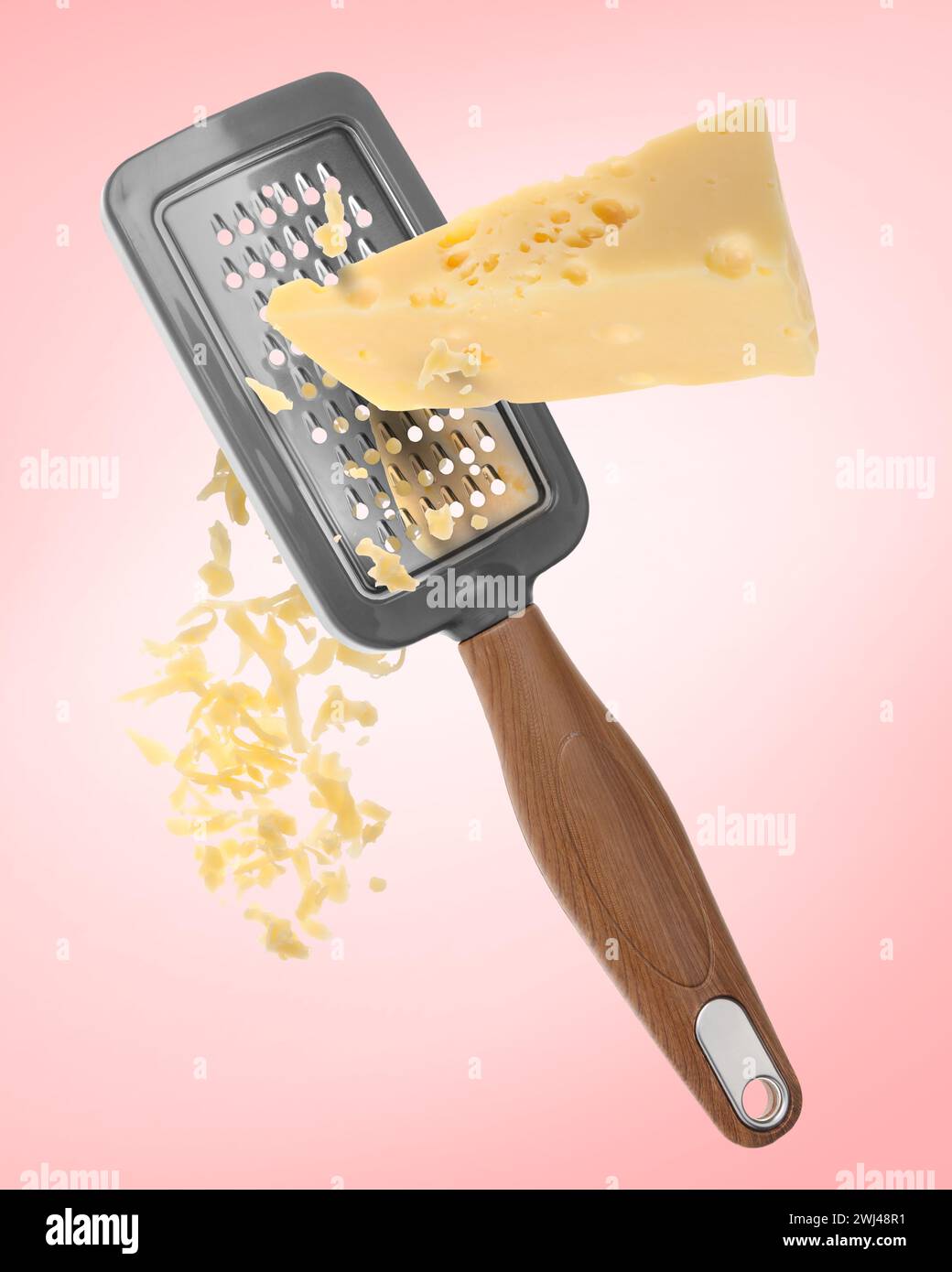 Grating cheese with hand grater on pink background Stock Photo - Alamy