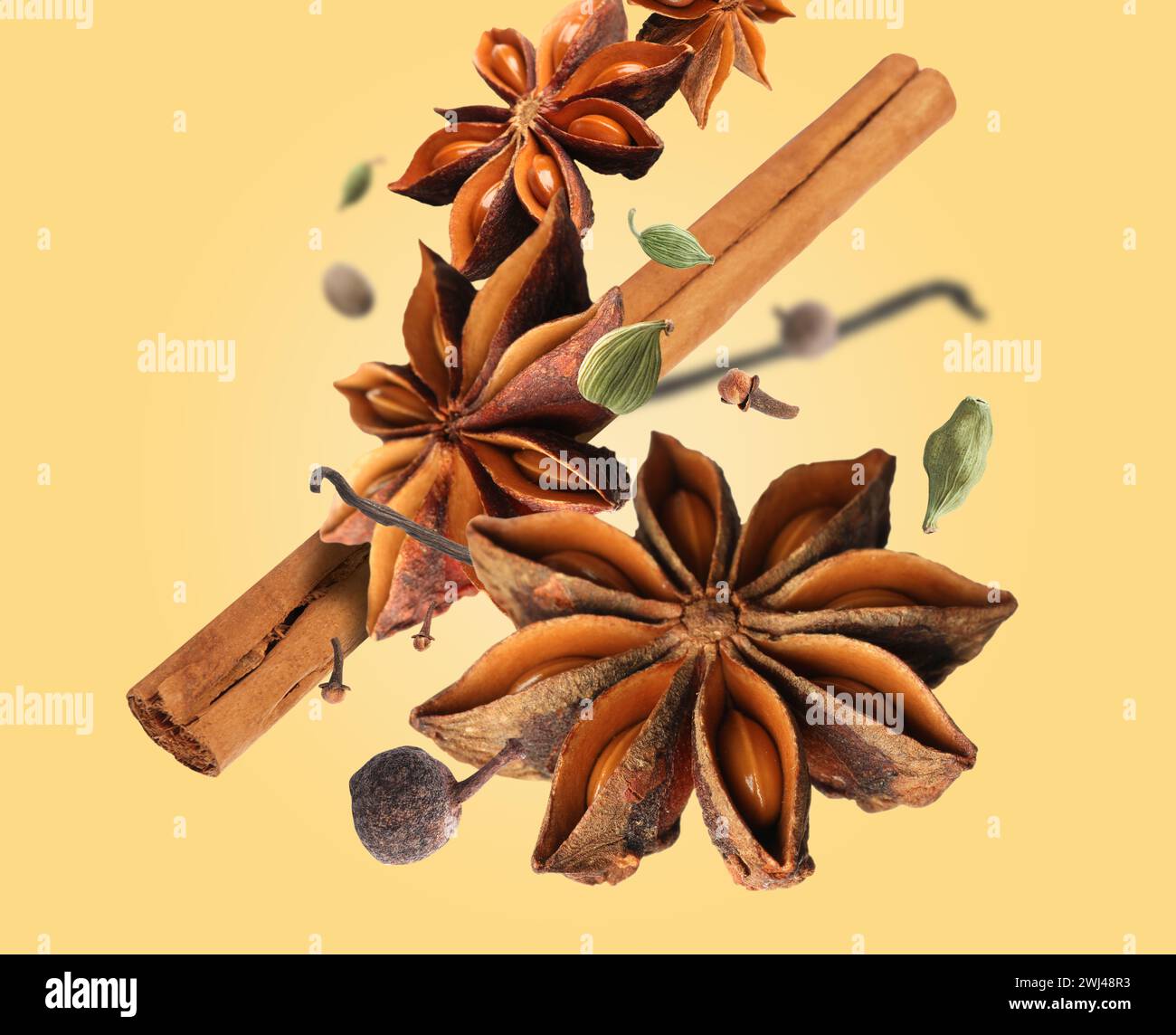 Different aromatic spices falling on golden background Stock Photo - Alamy