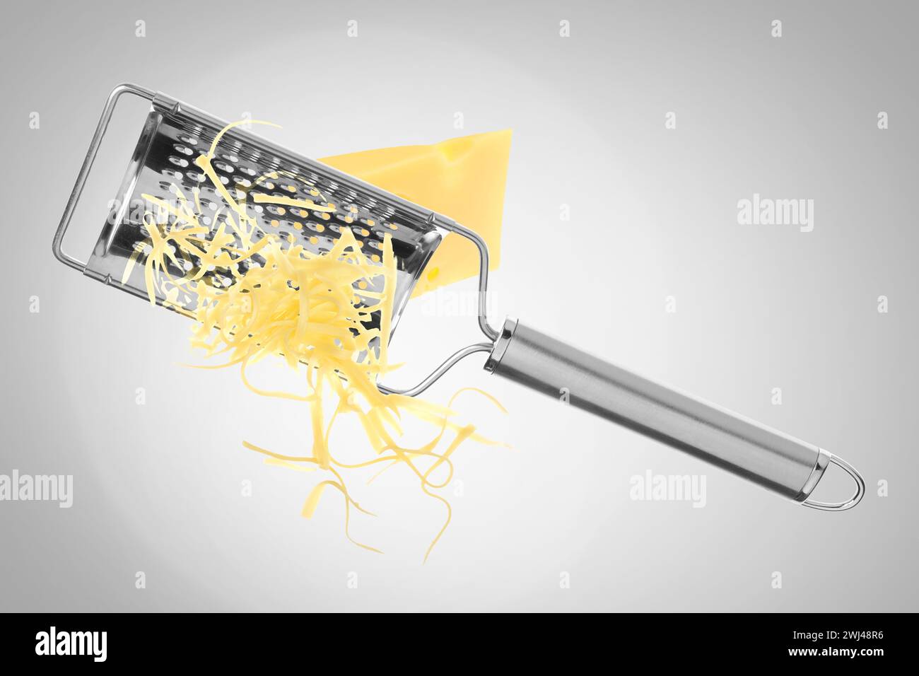 Grating cheese with hand grater on grey background Stock Photo - Alamy