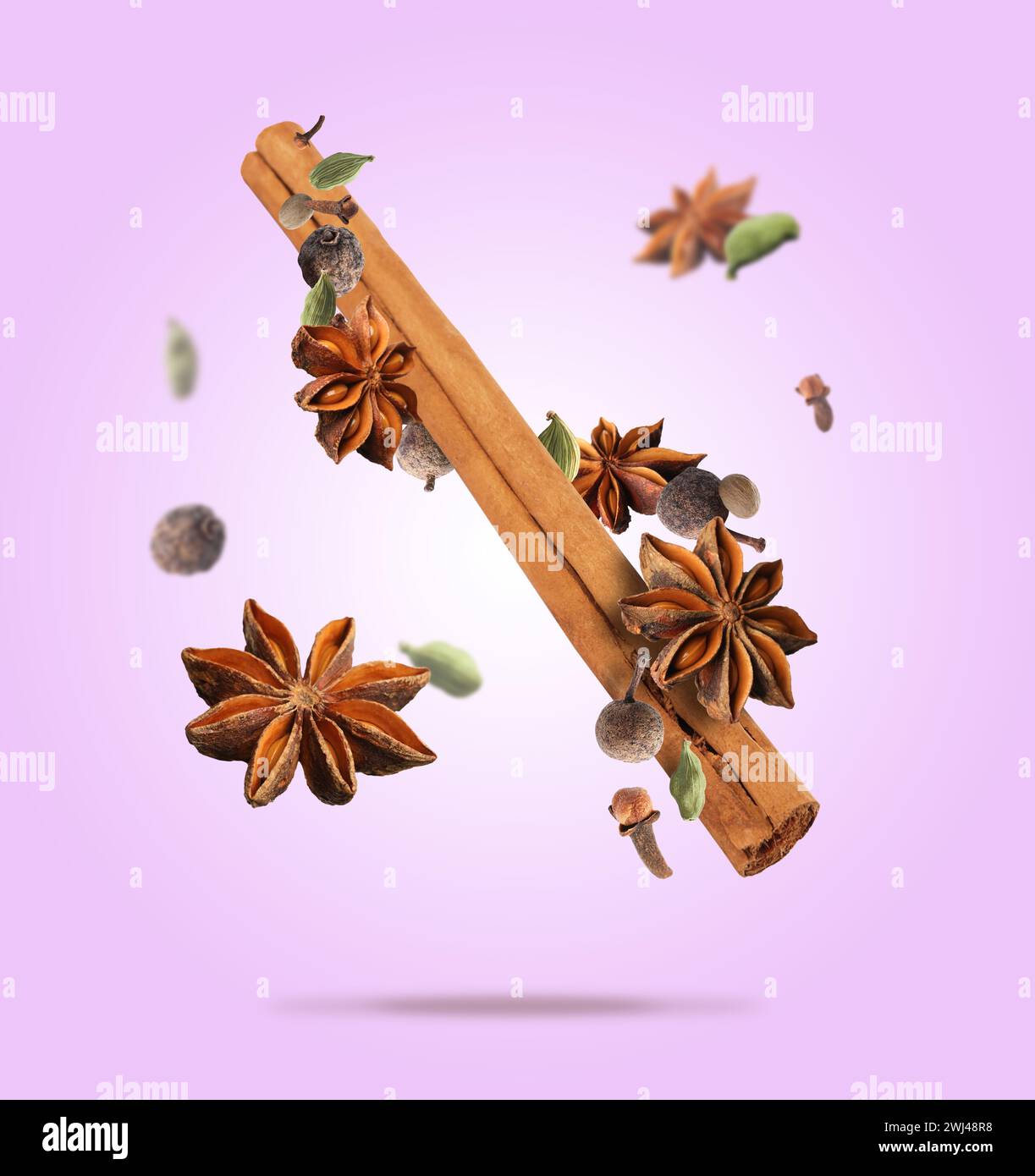 Different aromatic spices falling on violet background Stock Photo - Alamy