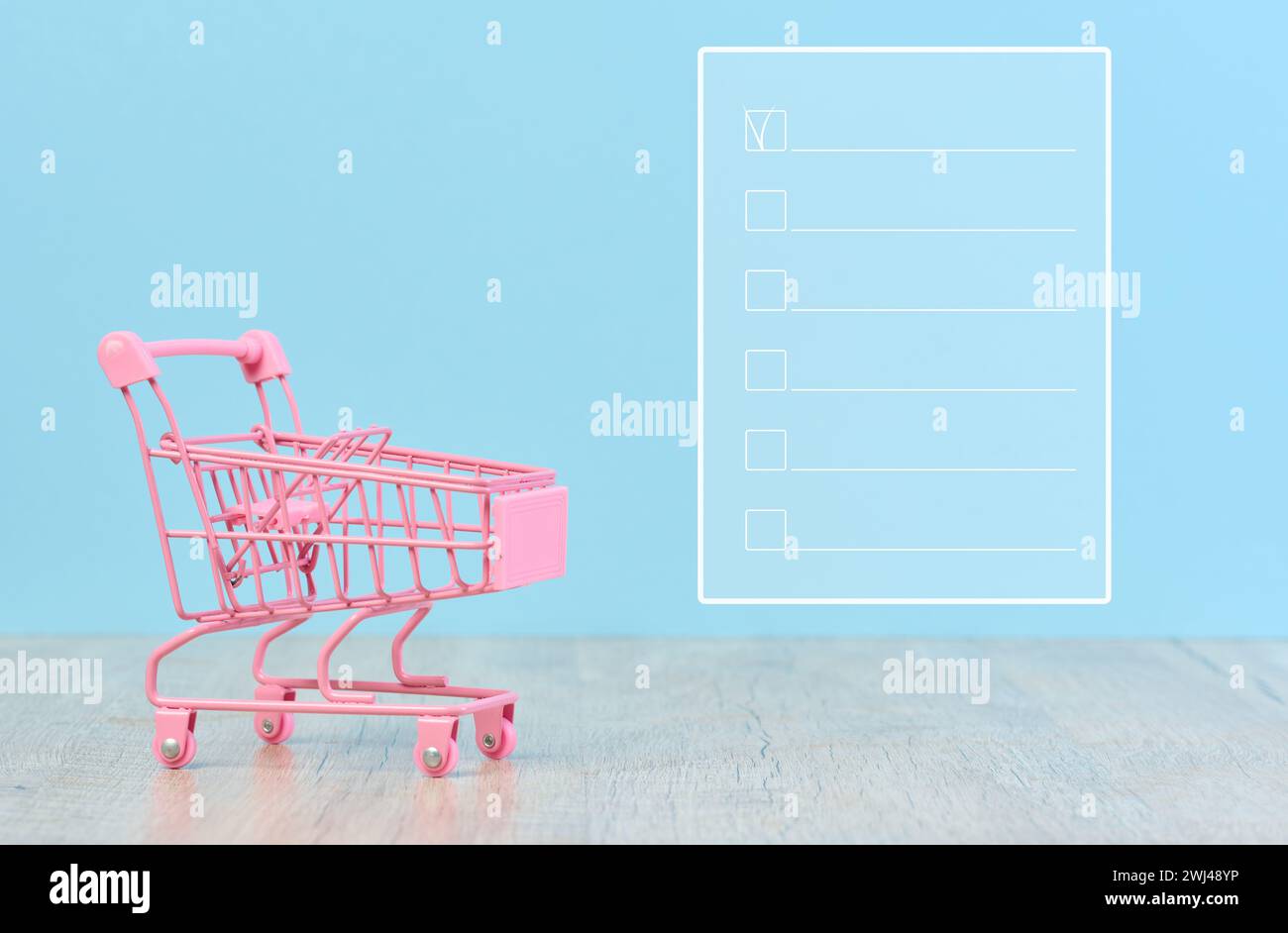 Miniature shopping cart and grocery shopping list on blue background ...