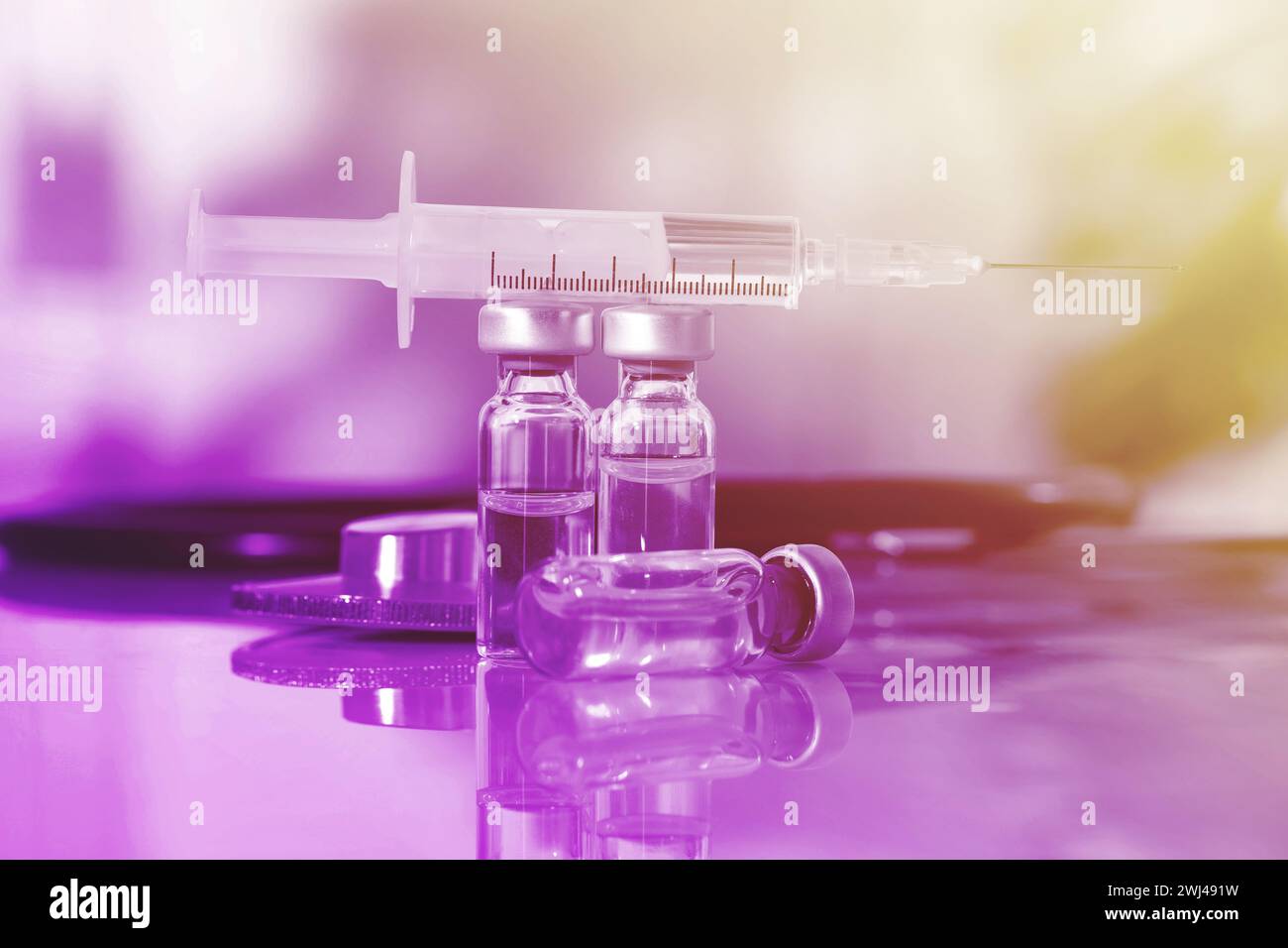 Syringe, glass vials and stethoscope on mirror surface. Color toned ...
