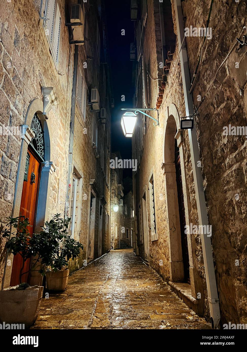 Ancient narrow street of a small medieval town illuminated by lanterns ...