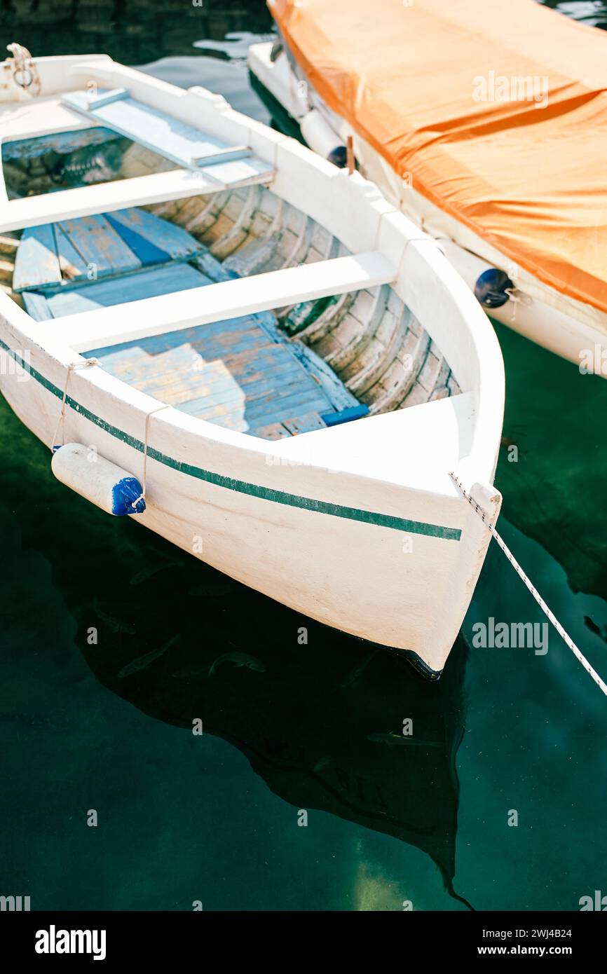 White fishing boat with a blue wooden bottom stands moored in the sea ...