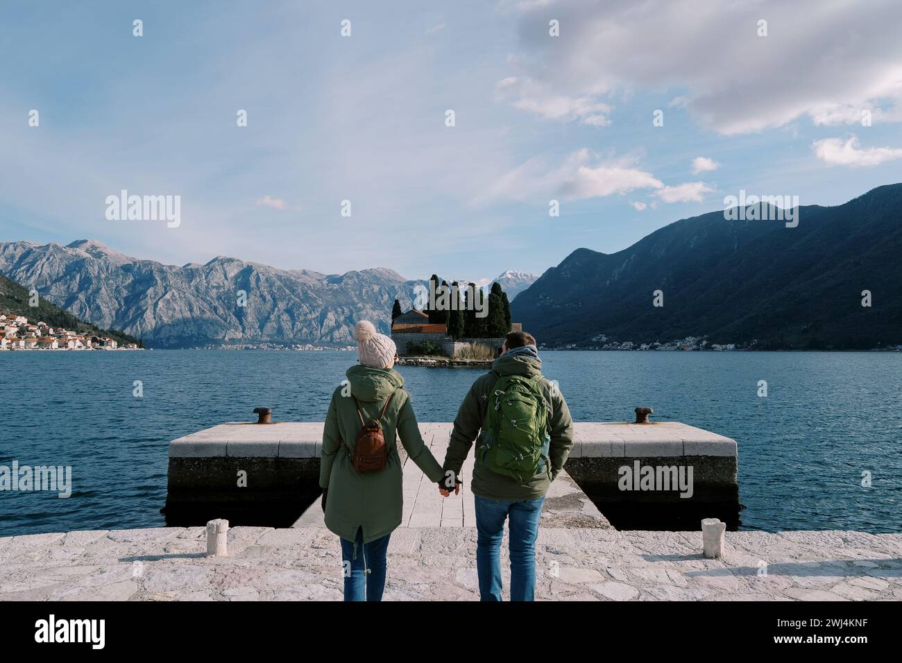 Man and woman walk holding hands along a pier overlooking St. George ...