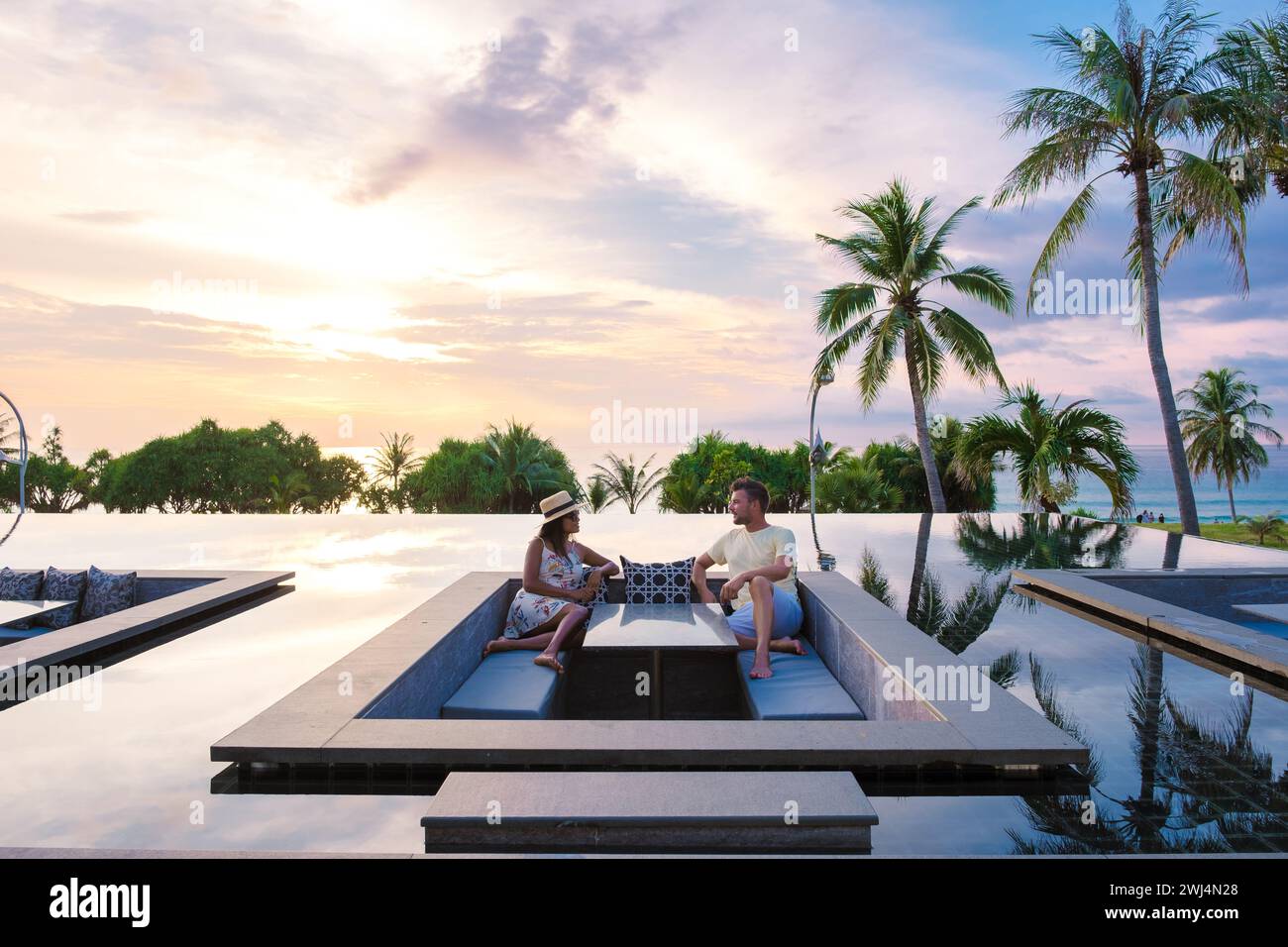 Couple watching the sunset in an infinity pool on a luxury vacation in ...