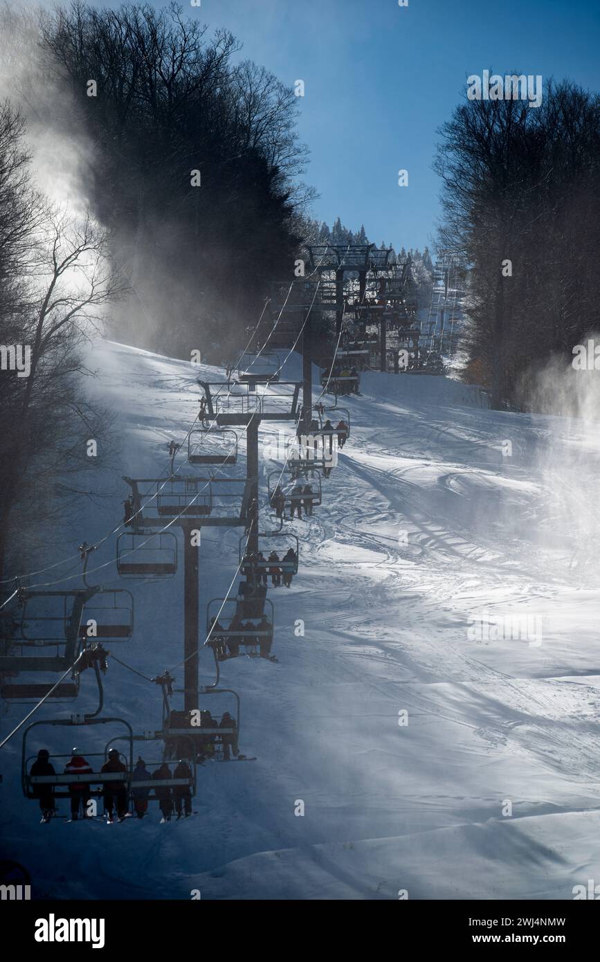 Skiers on a Sunday morning riding on the Sunapee Express Chairlift at ...