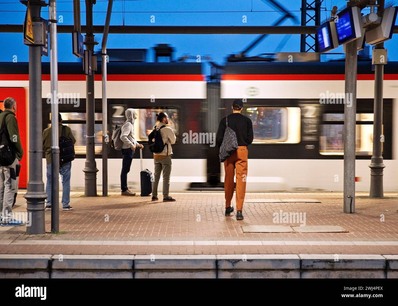Menschen auf dem Bahnsteig fruehmorgens mit vorbeifahrendem Zug, Hauptbahnhof, Witten, Nordrhein ...