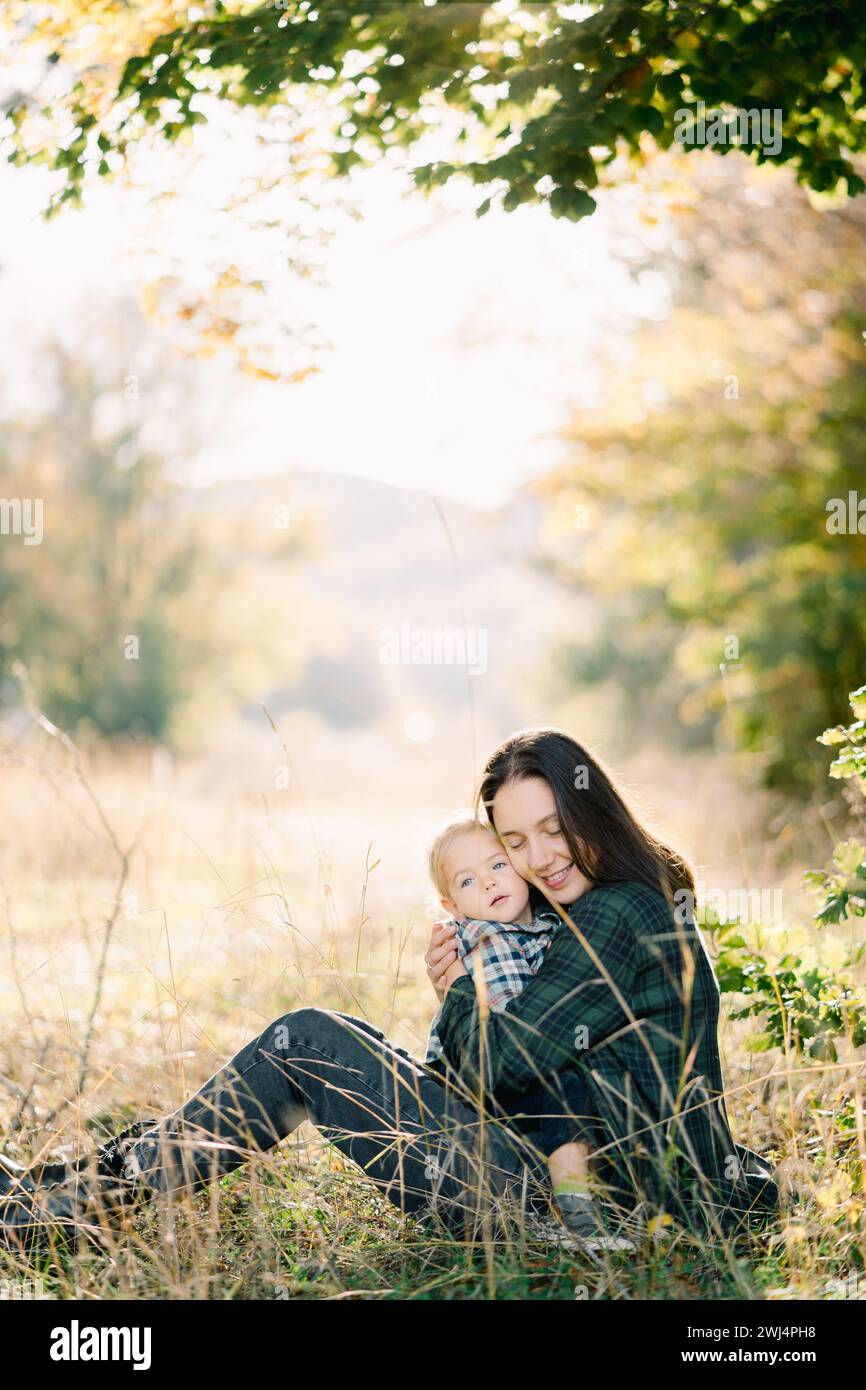 Smiling mother hugging her little daughter sitting on her lap on the ...