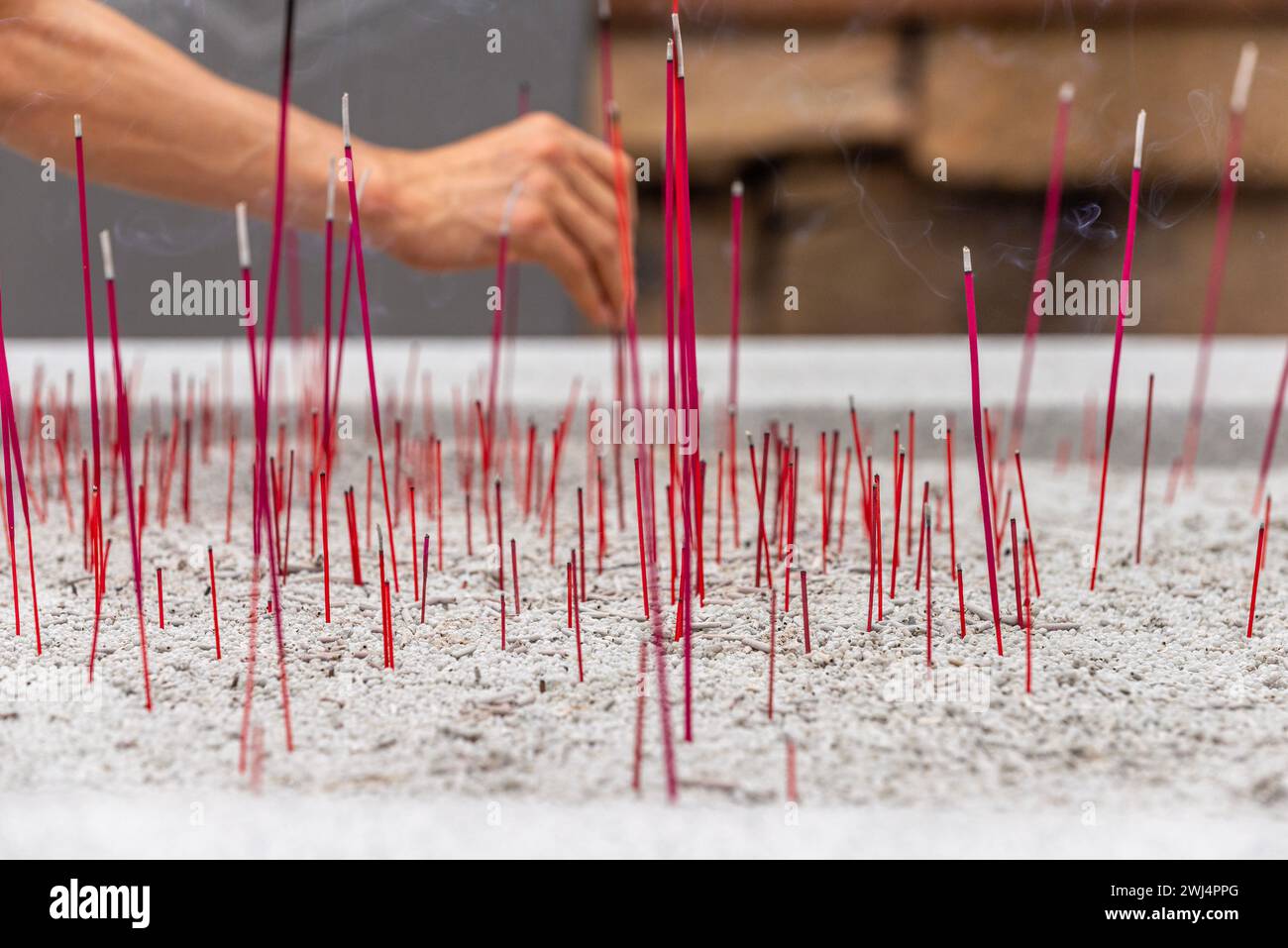 Incense sticks planted in sand at the entrance of a Buddhist temple ...