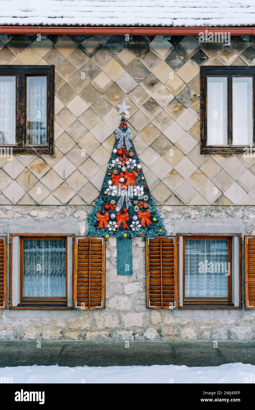 Felt Christmas tree with red bows and garlands hangs on the facade of ...