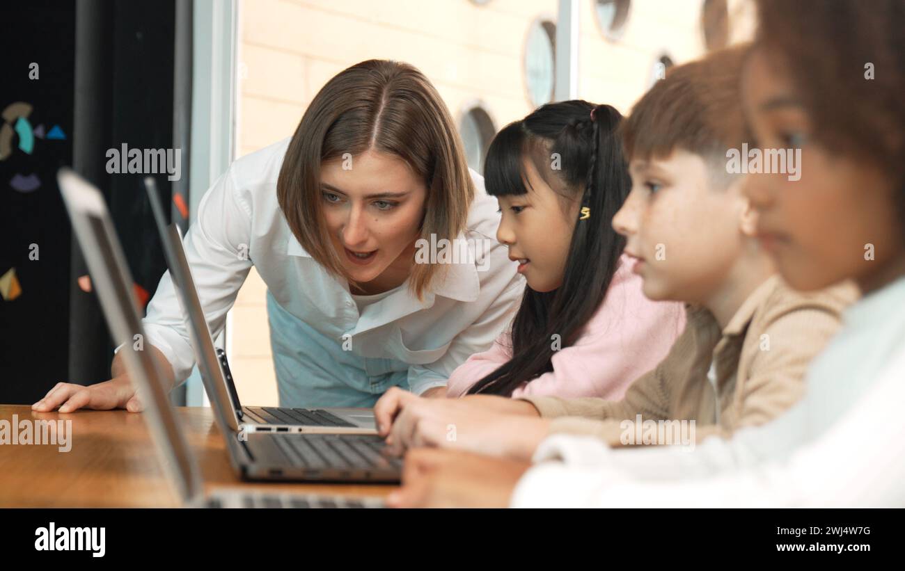 Smart teacher teaching and looking student using laptop at classroom ...