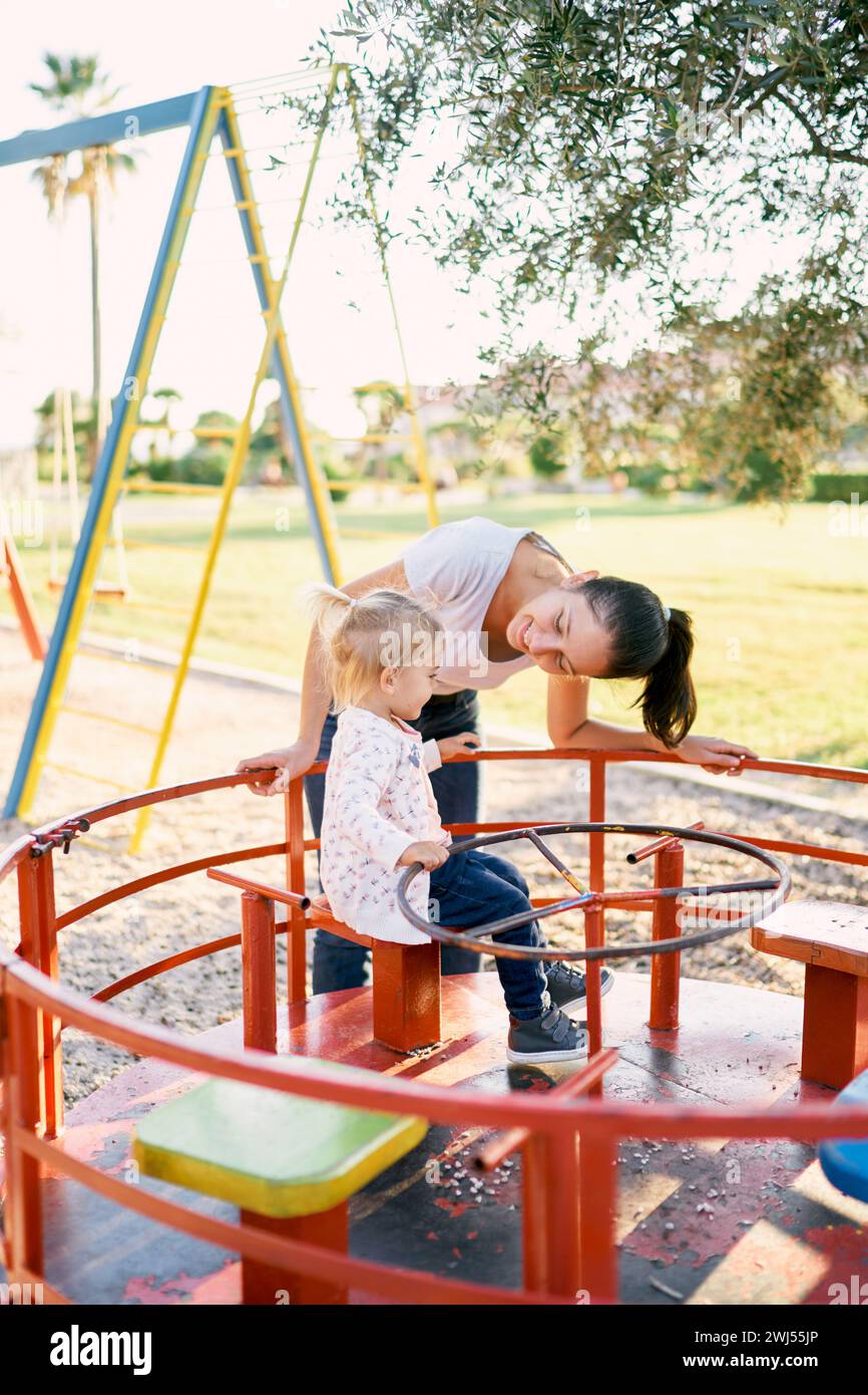 Mom leaned over to a little girl sitting on a carousel on the ...