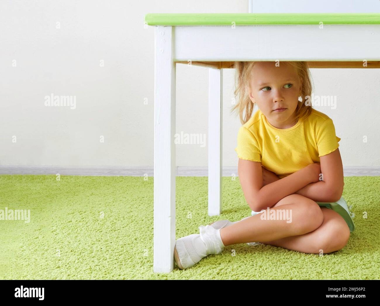 Scared Girl Hiding Under Table sitting on a floor Stock Photo - Alamy