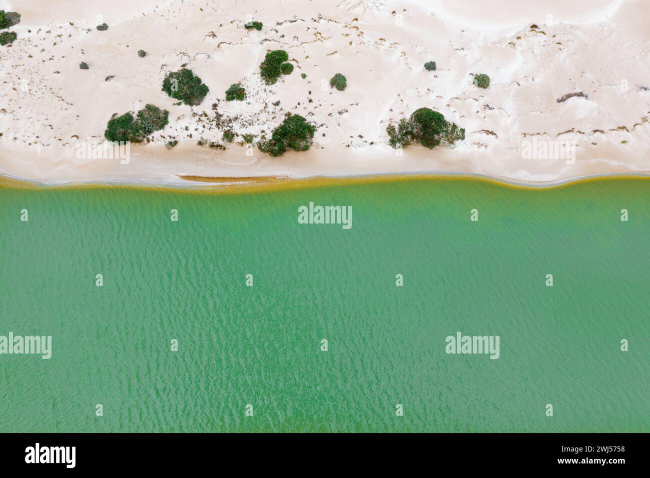 Aerial view of white sand dunes running down into a turquoise lagoon at ...