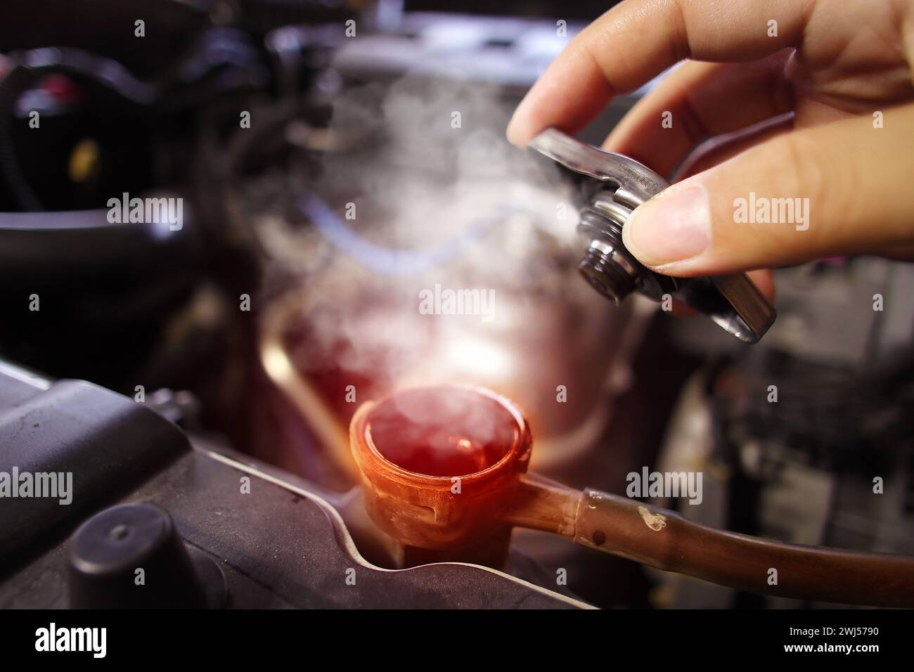 Auto mechanic hand opens the radiator cap with steam escaping around ...