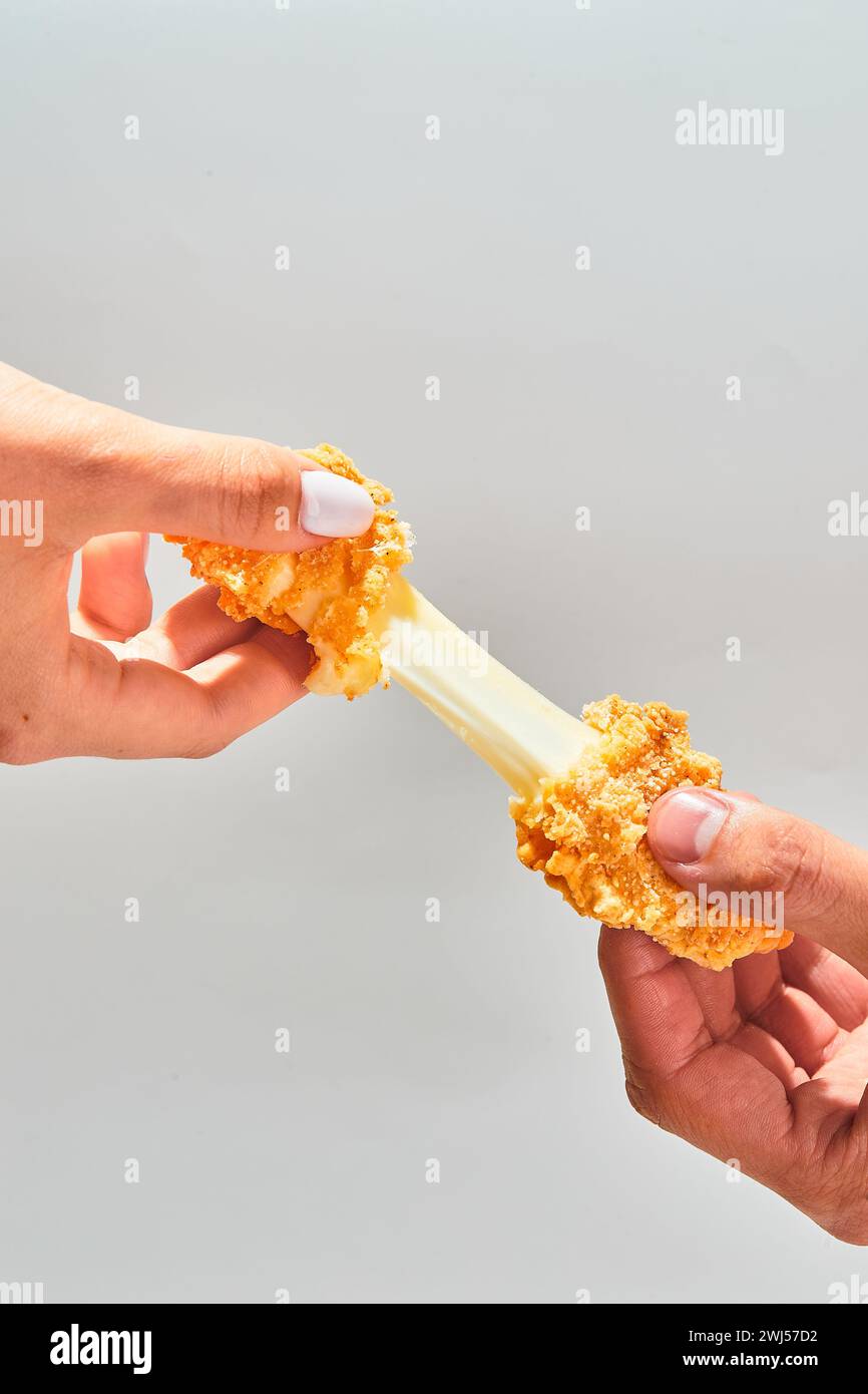 Crispy cheese fried breaded mozzarella cheese sticks stretch two hands ...