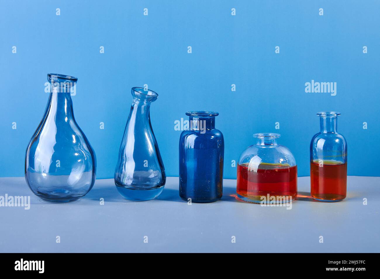 Set of various muted colored glass and metal bottles and vases on a ...