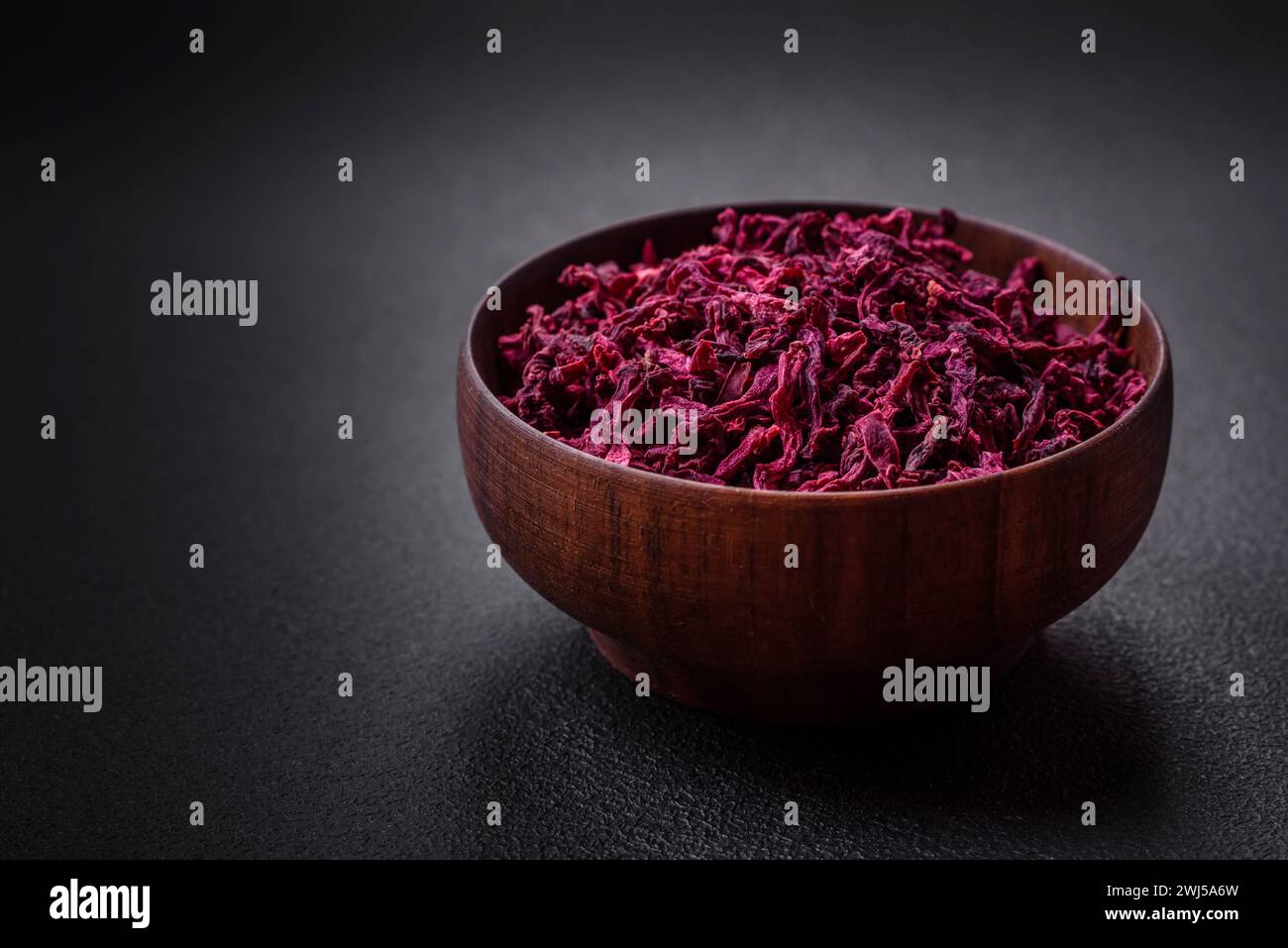 Dried beets in small slices in a wooden bowl on a black concrete ...