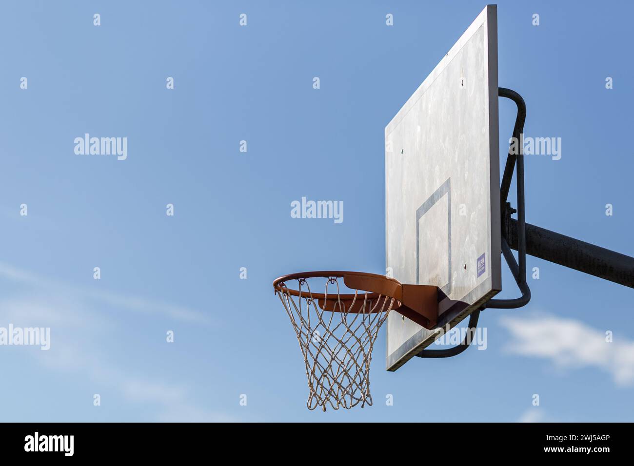 A basketball hoop and backboard outdoors with blue sky and net Stock ...