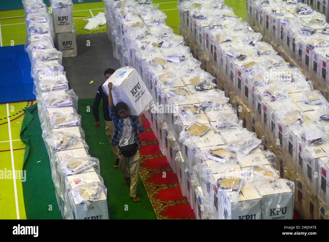 Jakarta, Indonesia. 13th Feb, 2024. A staff member carries a ballot box ...