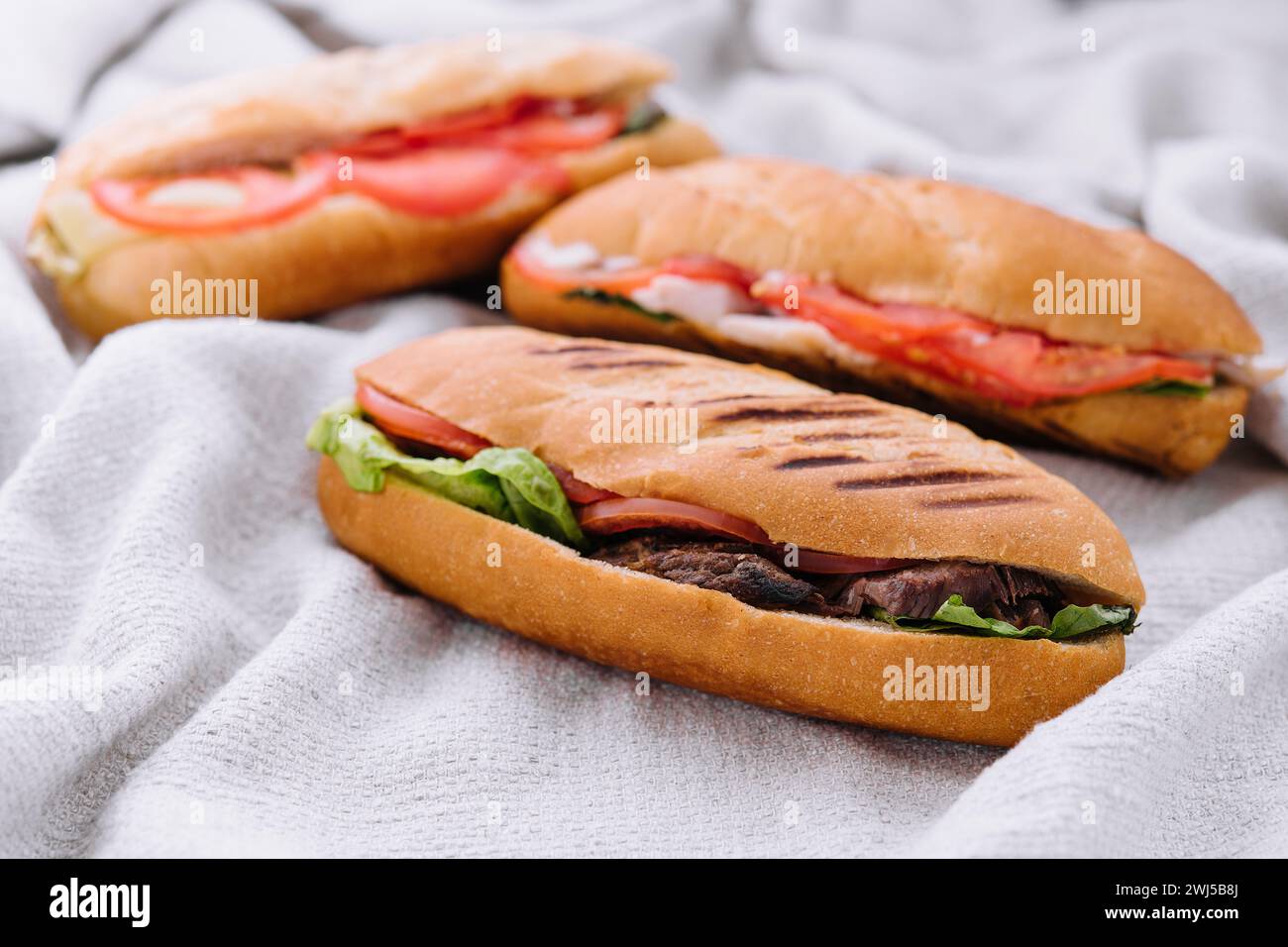Three fresh sub sandwiches on a cloth background Stock Photo - Alamy