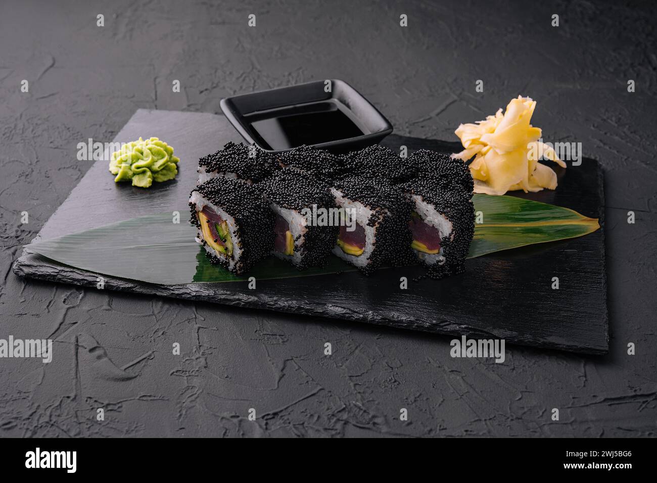 California rolls covered black tobiko on a black board Stock Photo - Alamy