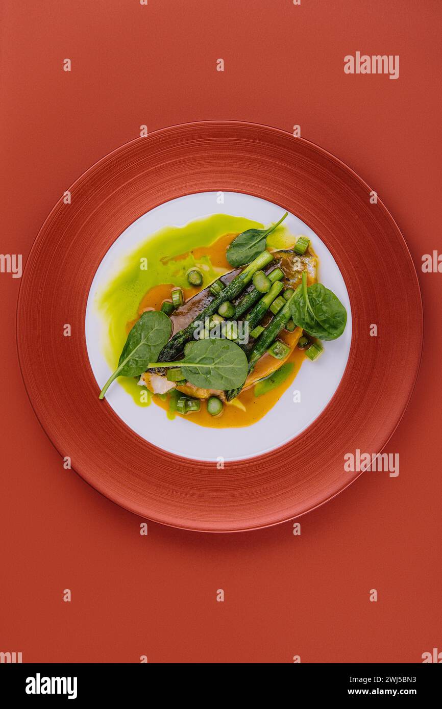 Fish dish - fried cod fillet with asparagus and basil served on red ...