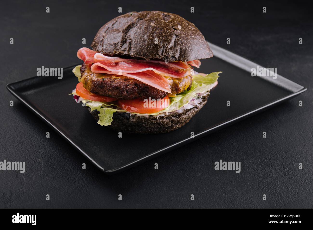 Modern black burger with prosciutto ham Stock Photo - Alamy
