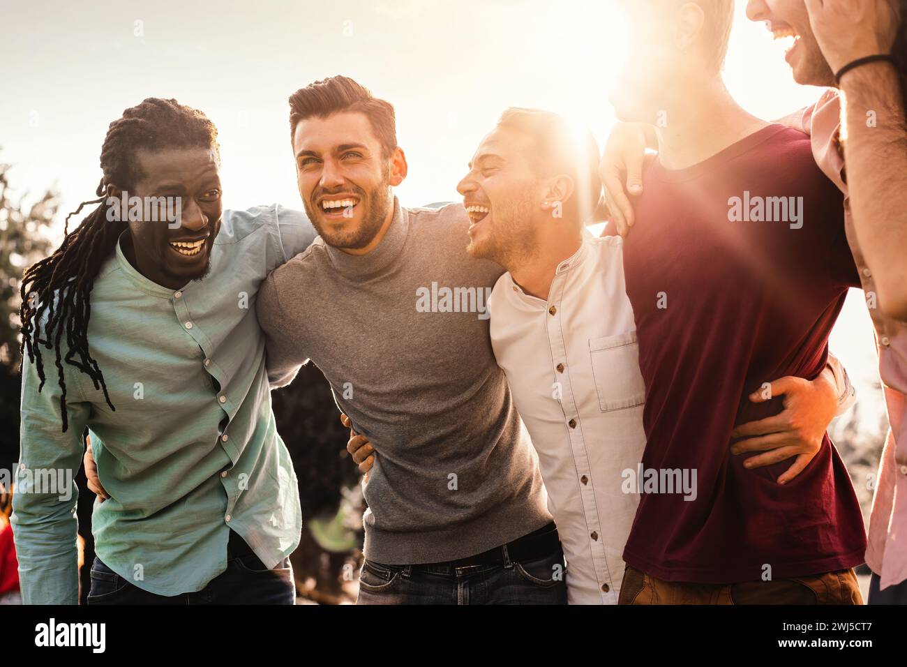 Group of multiracial men laughing together outdoors - Expression of joy and friendship among ...