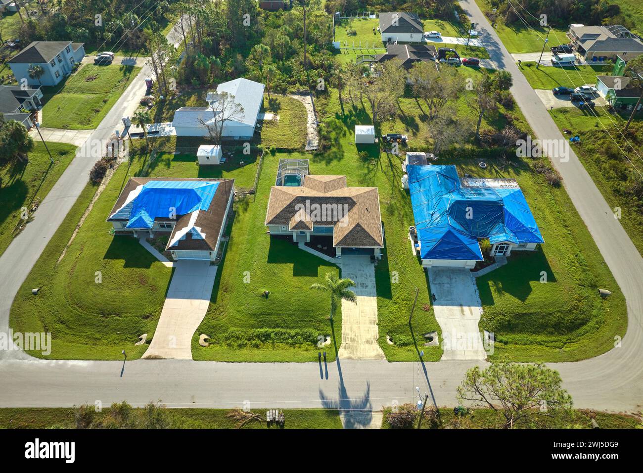 Aerial view of damaged in hurricane Ian house roof covered with blue ...