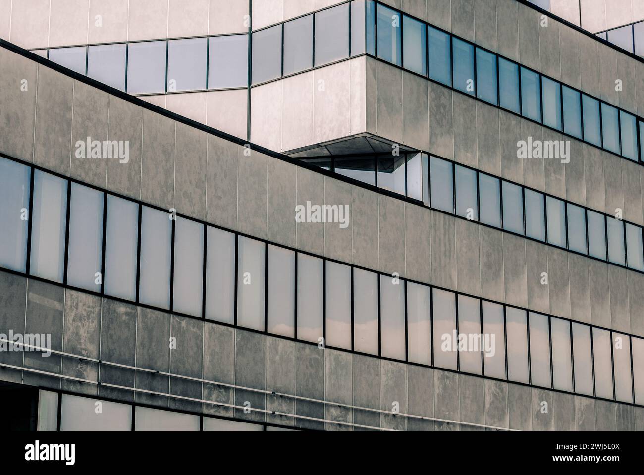 Gray high concrete building with reflection of the sky and clouds in ...