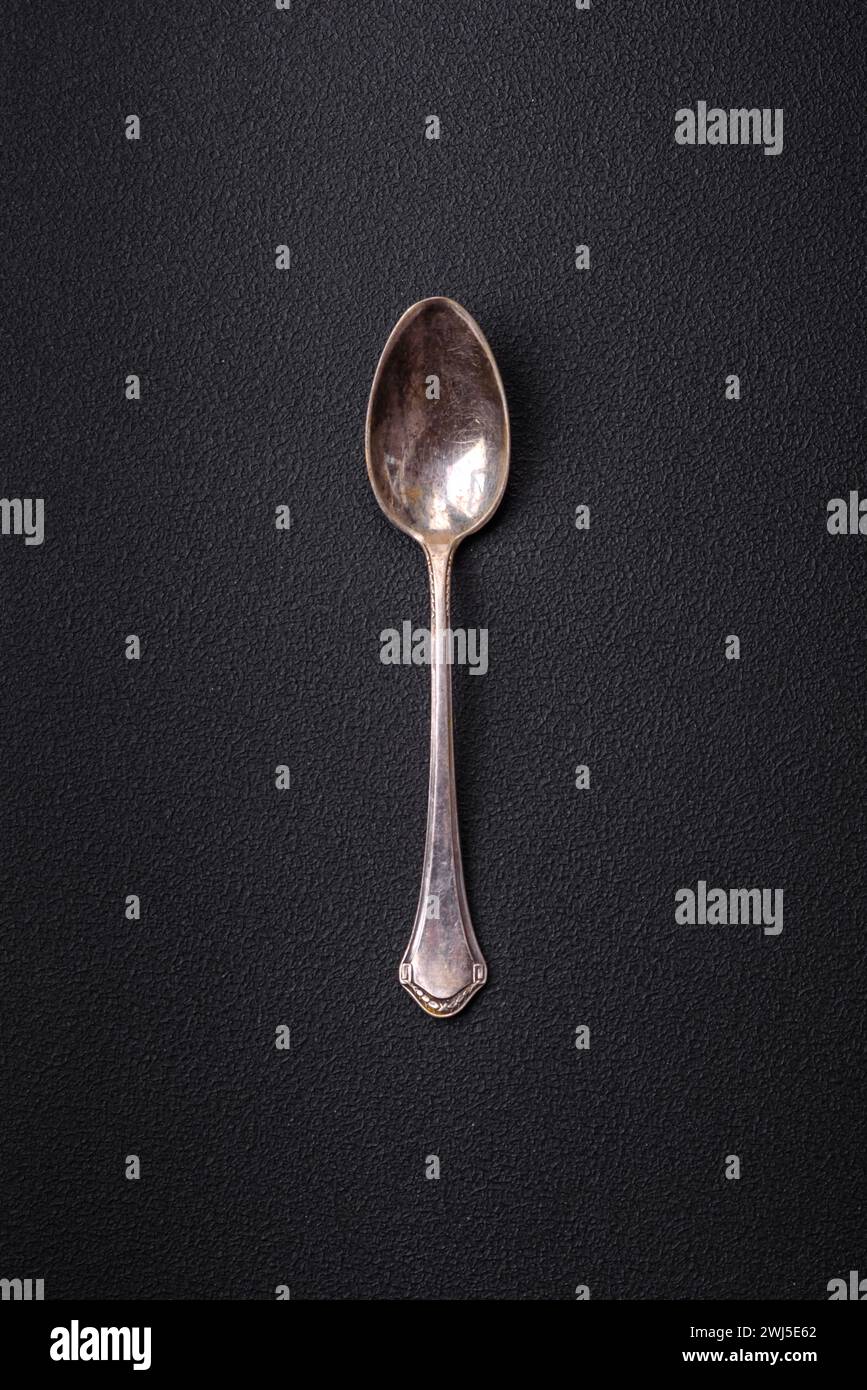 Empty metal spoon on dark textured concrete background Stock Photo - Alamy