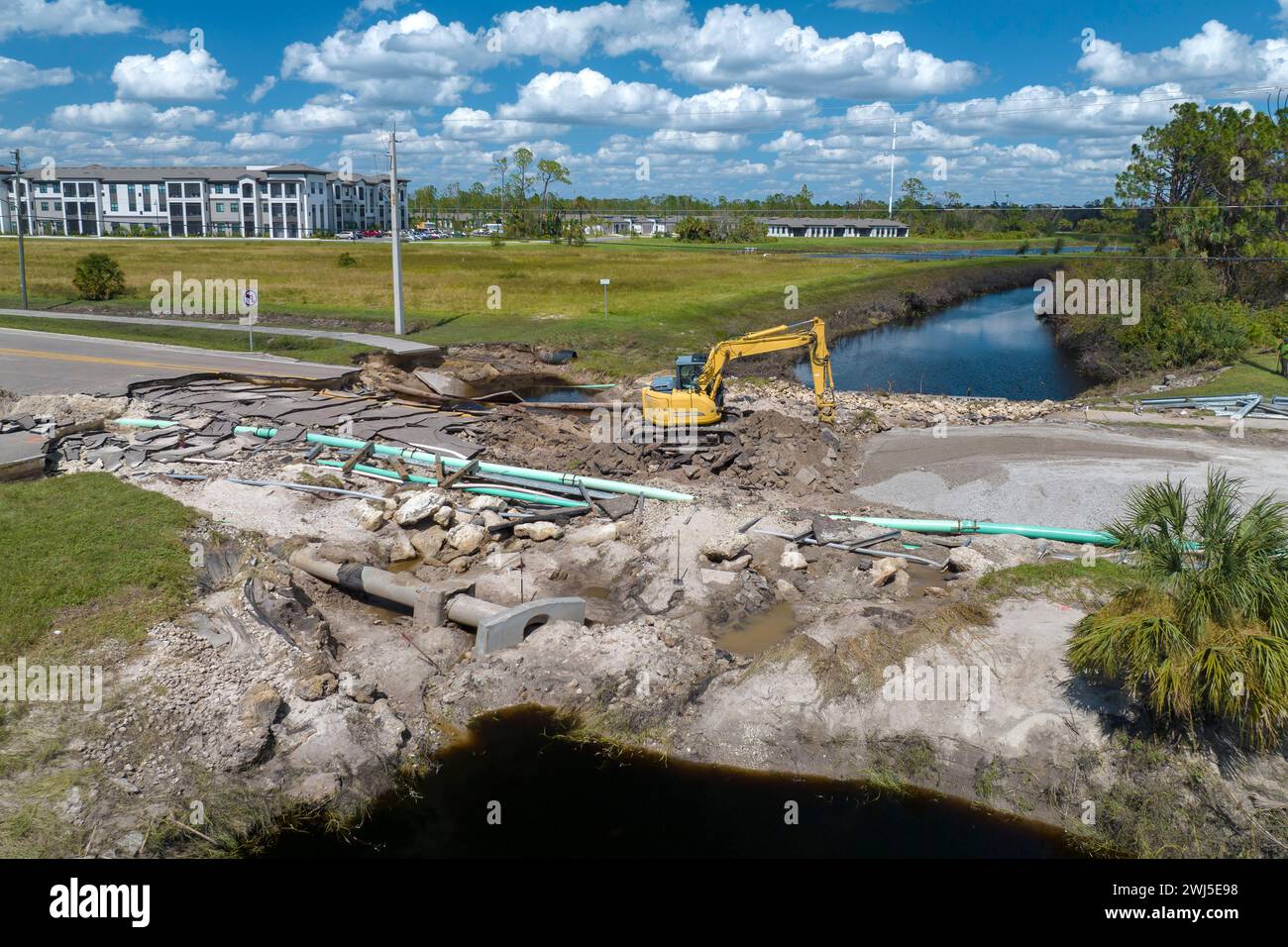 Road construction. Excavator repairing destroyed bridge after hurricane ...