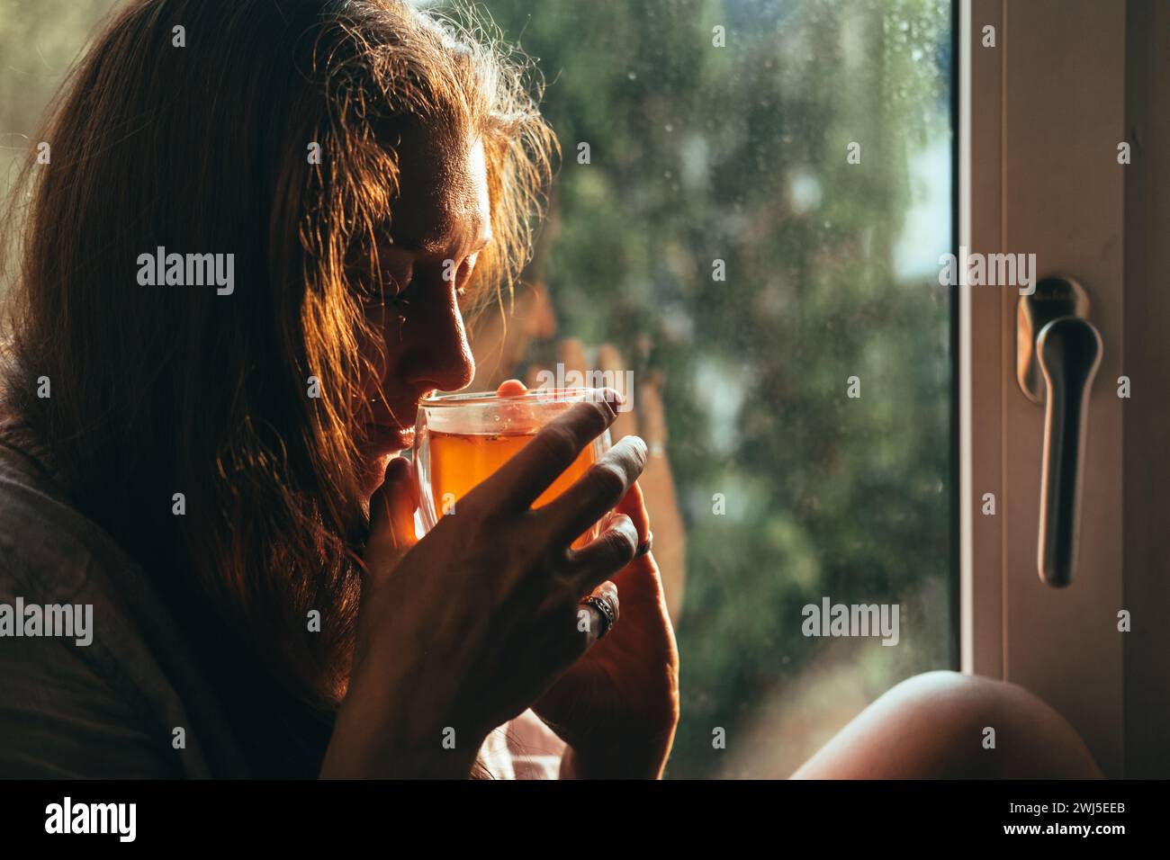 Woman Enjoying Tea by Rainy Window Stock Photo - Alamy
